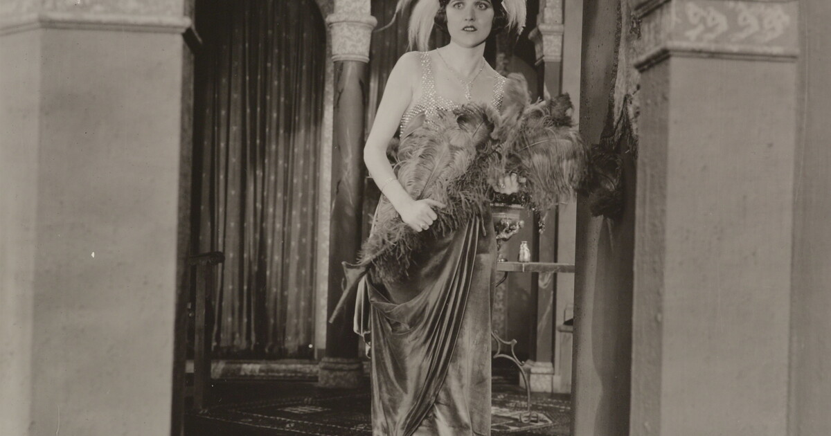 [Agnes Ayres in formal wear, standing in archway, "Forbidden Fruit ...