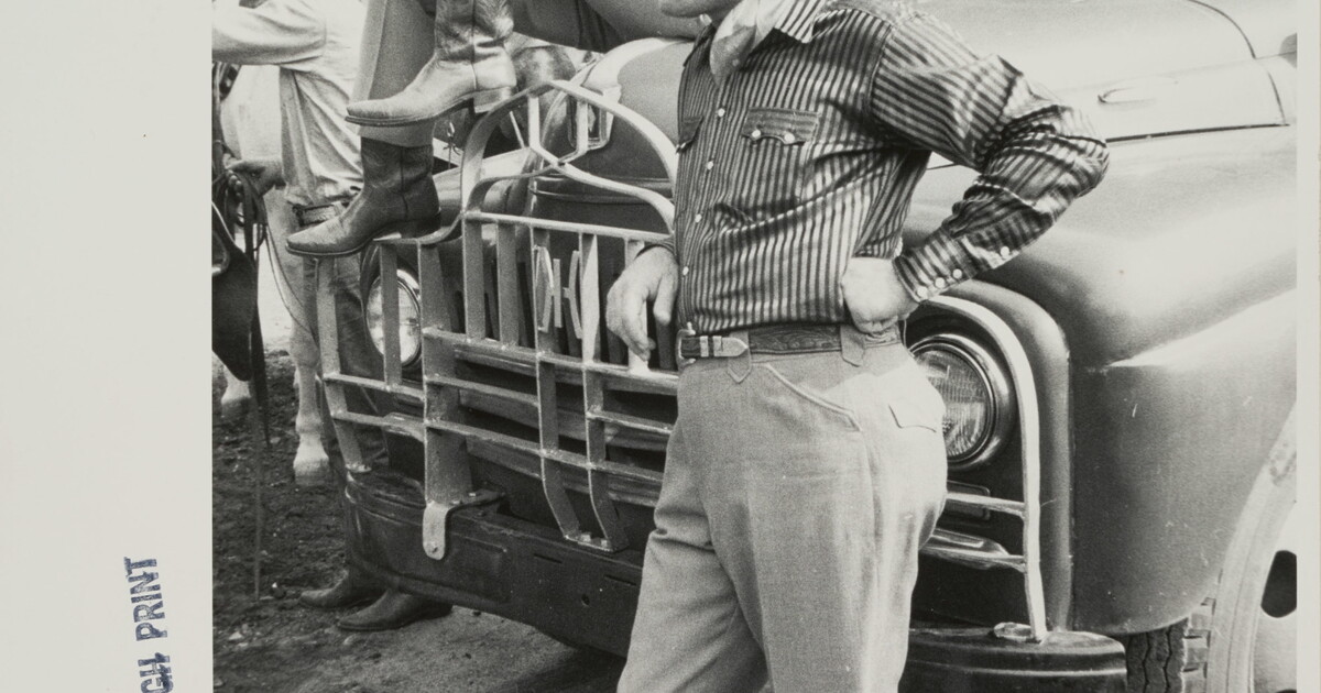 [Don Coates, Rodeo announcer, next to cowboy sitting on the hood of a ...